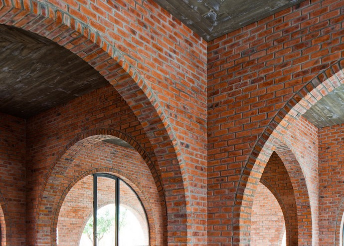 A grid of 24 red bricks arches frames the interior of the space which ...